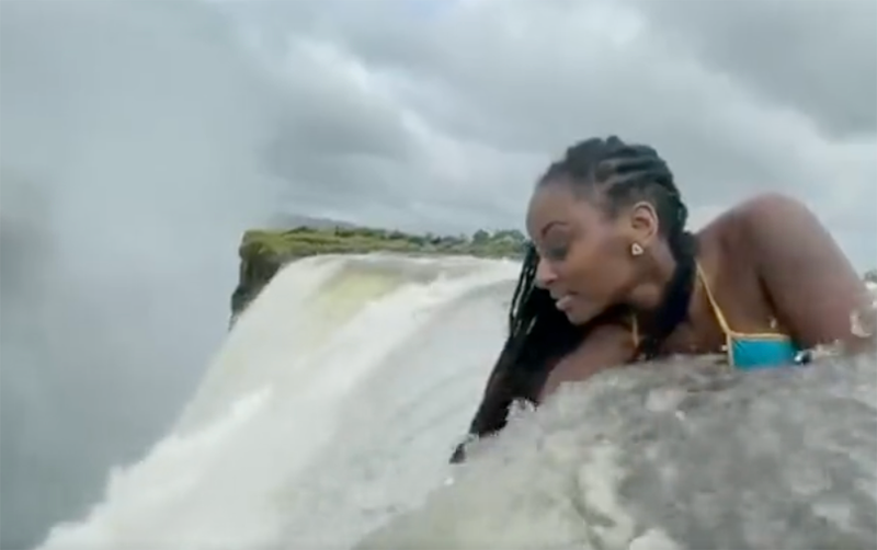 Woman Leans Over Edge Of 360 feet tall Victoria Falls In Breathtaking